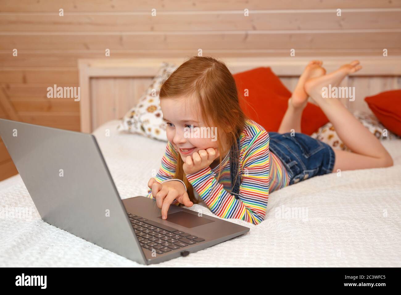 A little girl looks at the computer with different emotions. Girl plays ...