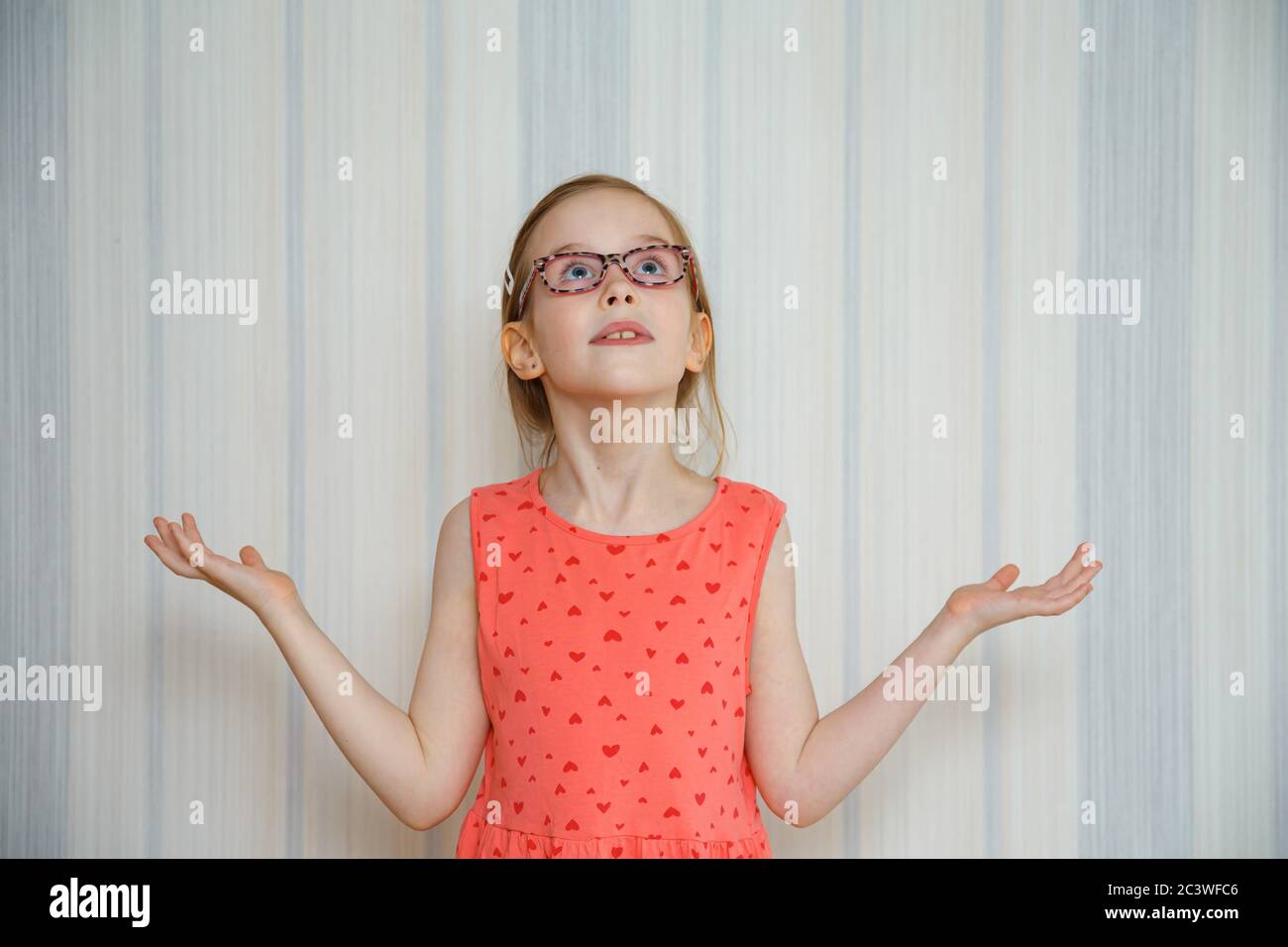 Little girl makes a gesture that understands nothing and looks up Stock ...
