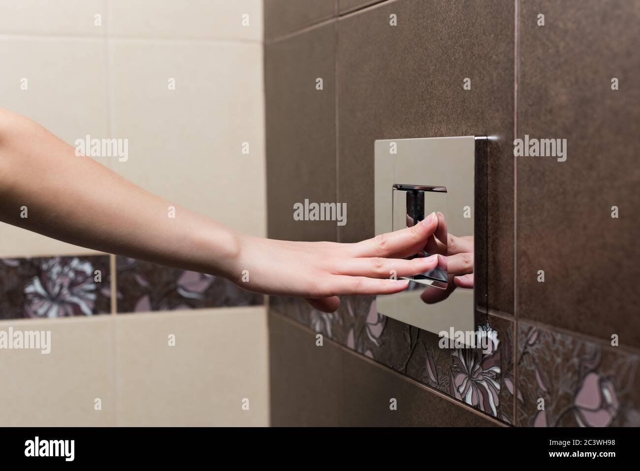 Girl's hand presses a large flush button in the toilet Stock Photo - Alamy