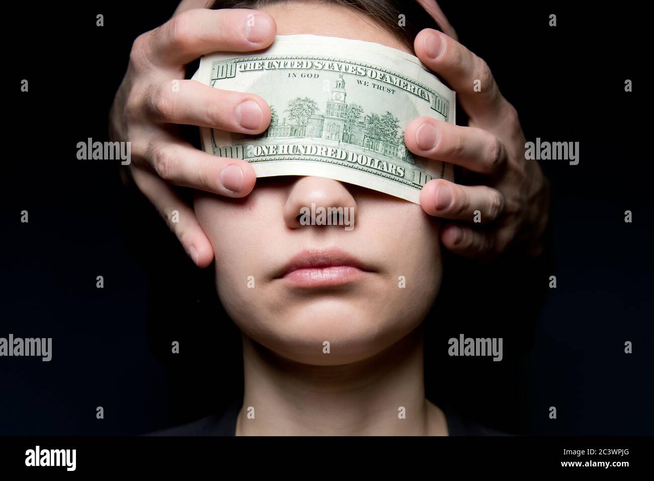 The eyes of a young woman are closed by a hundred-dollar bill. Money is ...