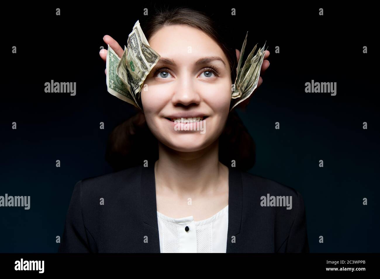 woman smiles coldly and looks into the dark. Her ears are covered with ...