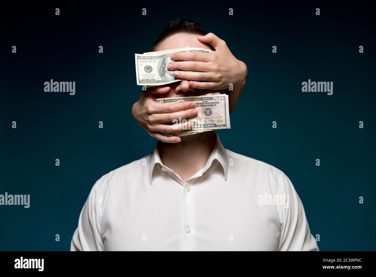 The mouth and eyes of a man in a white shirt are closed with dollars ...