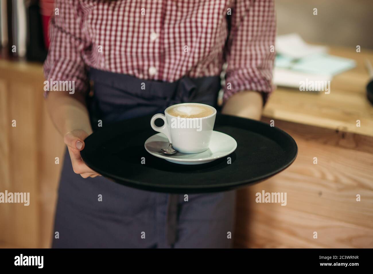 Waitress offering a cup of coffee in cafe. cappuchino Stock Photo - Alamy