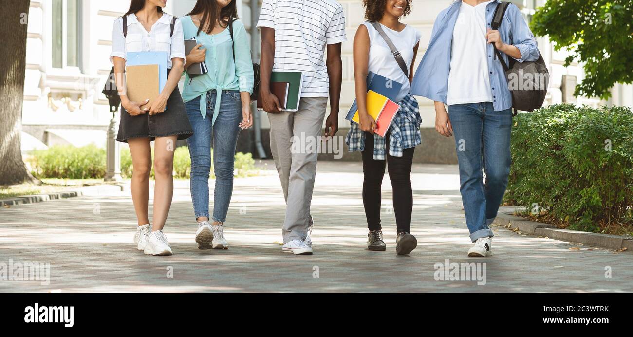 Cheerful teen students leaving college after classes, walking together ...