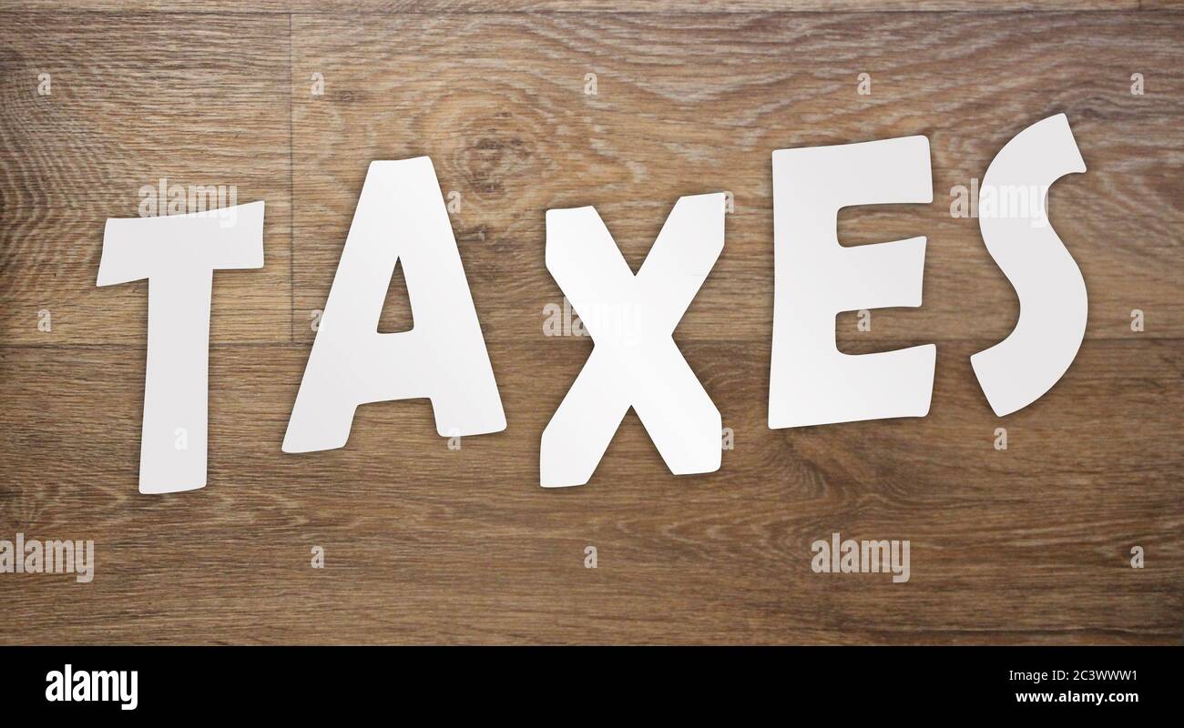 Taxes word letters cut from white paper on wooden background. Taxes ...