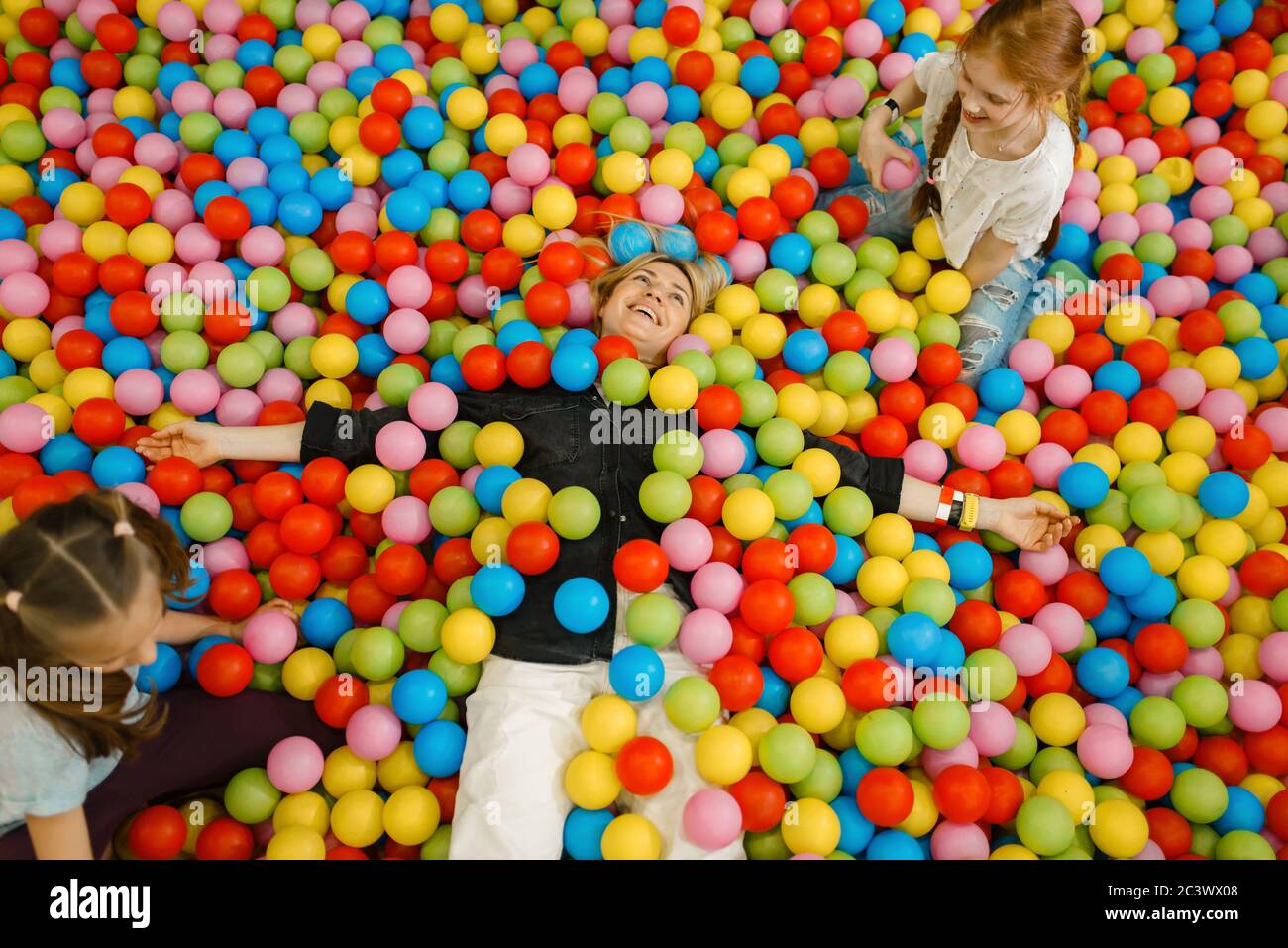Children with mother lying among colorful balls Stock Photo - Alamy