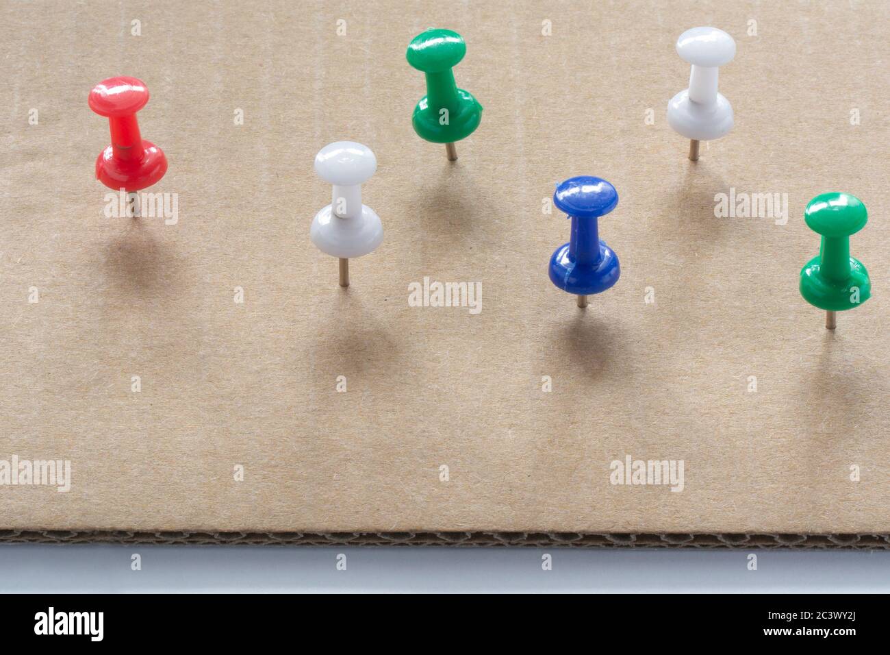 Multi colored Push Pins on White cardboard paper texture Background ...