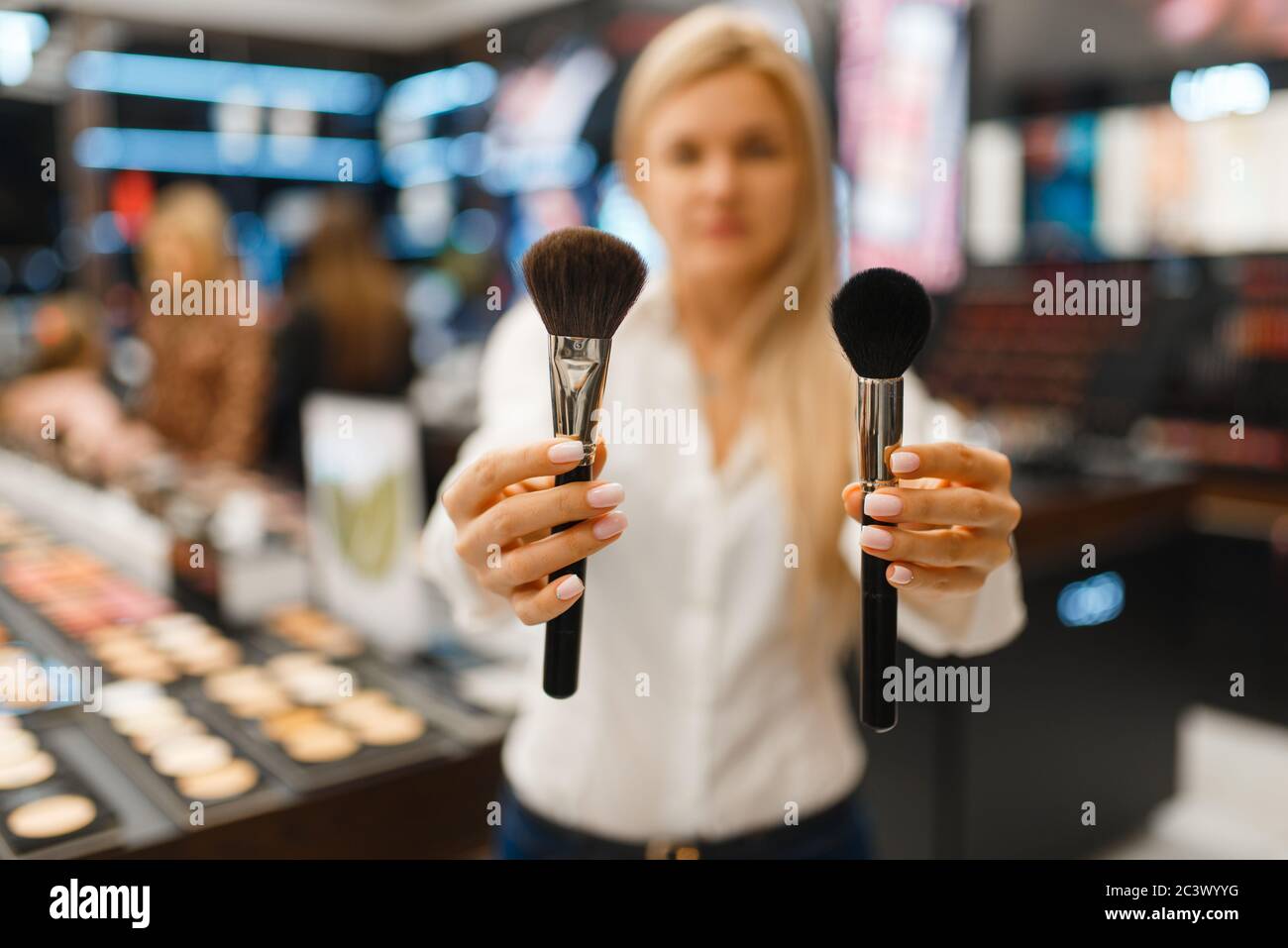 Woman shows brushes in cosmetics store Stock Photo - Alamy
