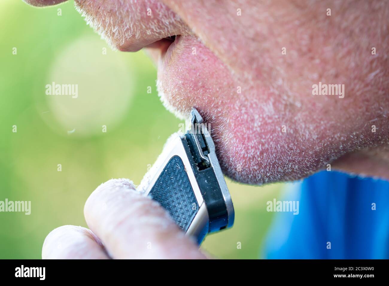 A man cuts his white beard with a clipper Stock Photo - Alamy
