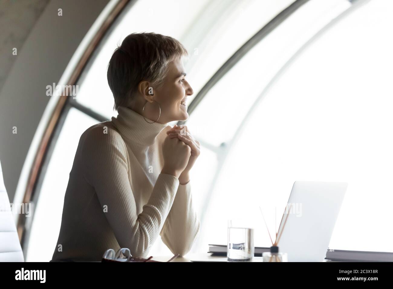 Businesswoman sitting at workplace finish workday look out the window ...