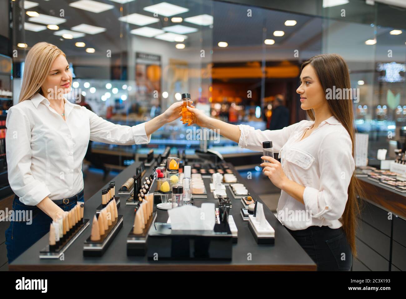 Cosmetician at counter and woman, cosmetics store Stock Photo - Alamy