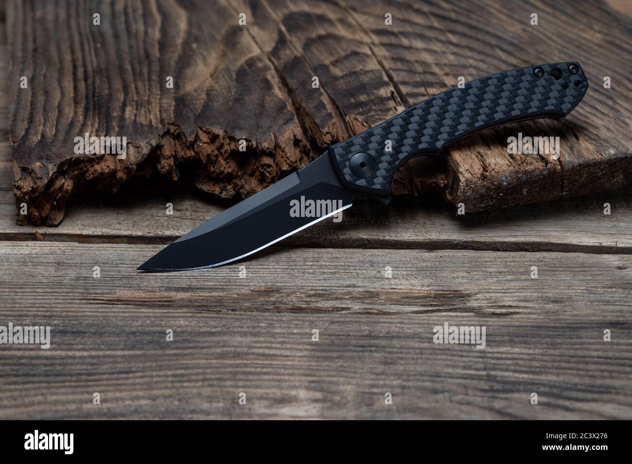 A sharp knife with a black carbon handle and a black blade. Wood ...