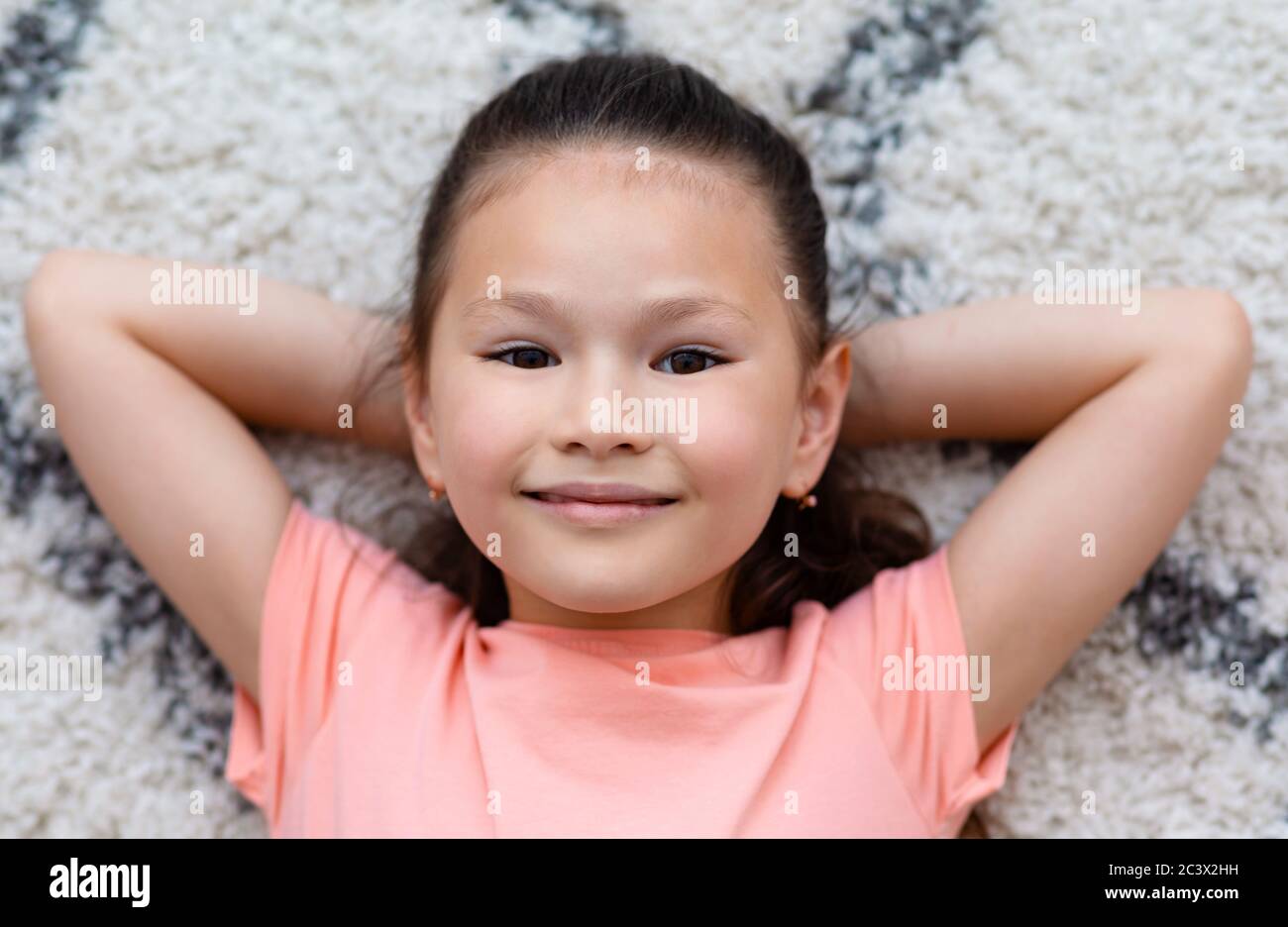Adorable Kid Girl Smiling Lying On Floor Indoors, Above View Stock ...