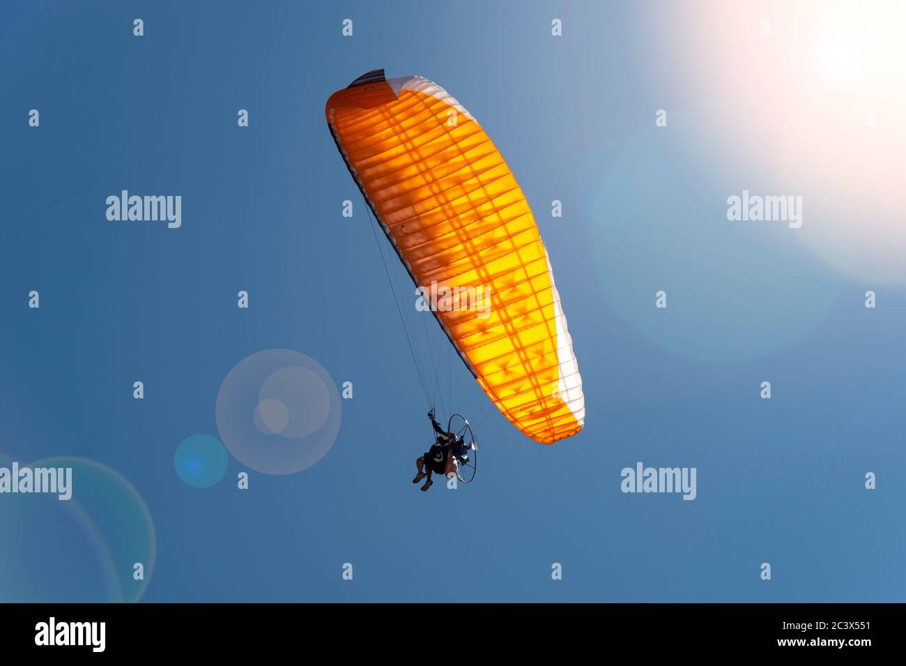 Motorised paraglider with blue sky and sun lens flare Stock Photo - Alamy