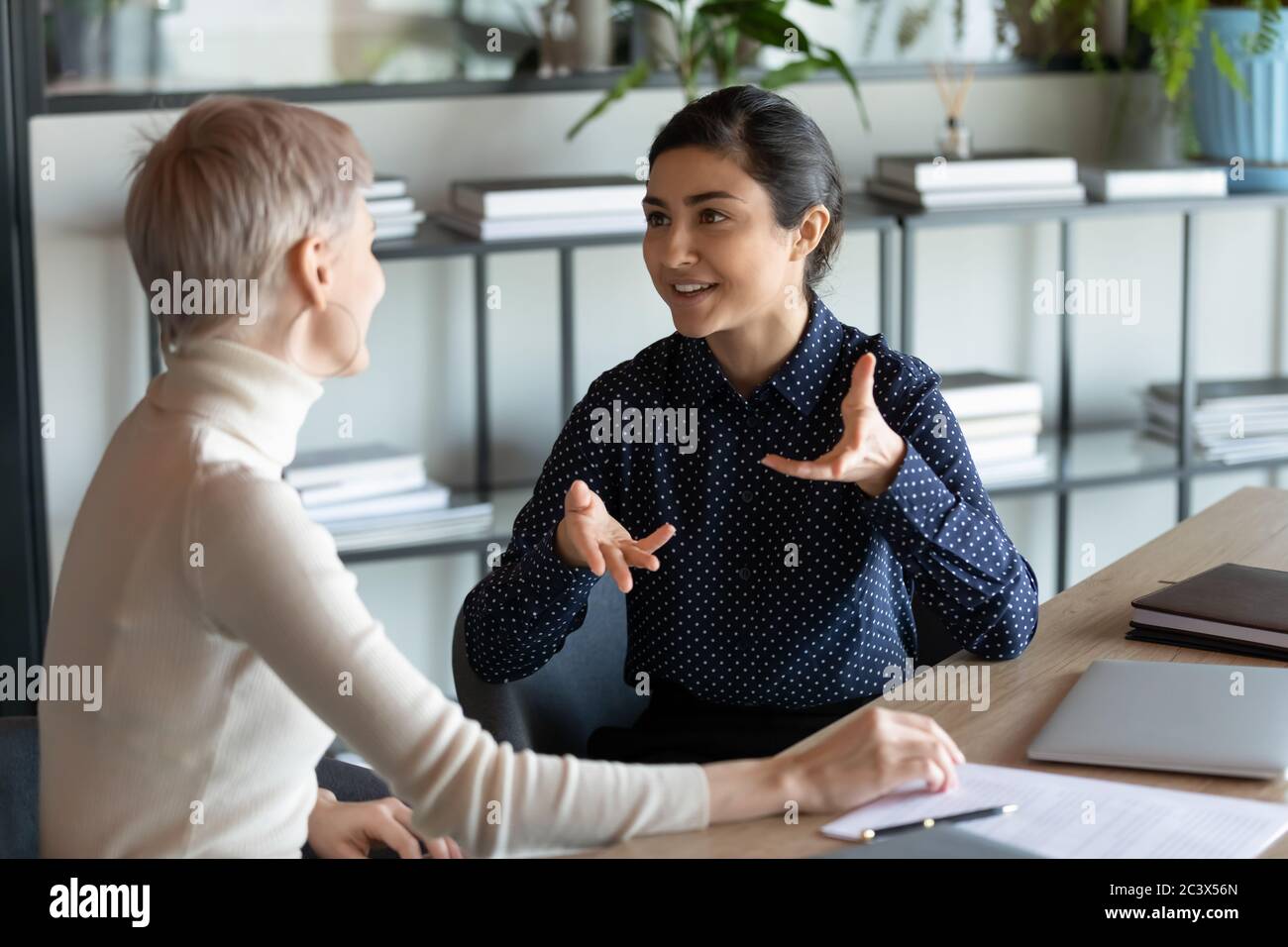 Multiracial colleagues talking while working on common project in ...