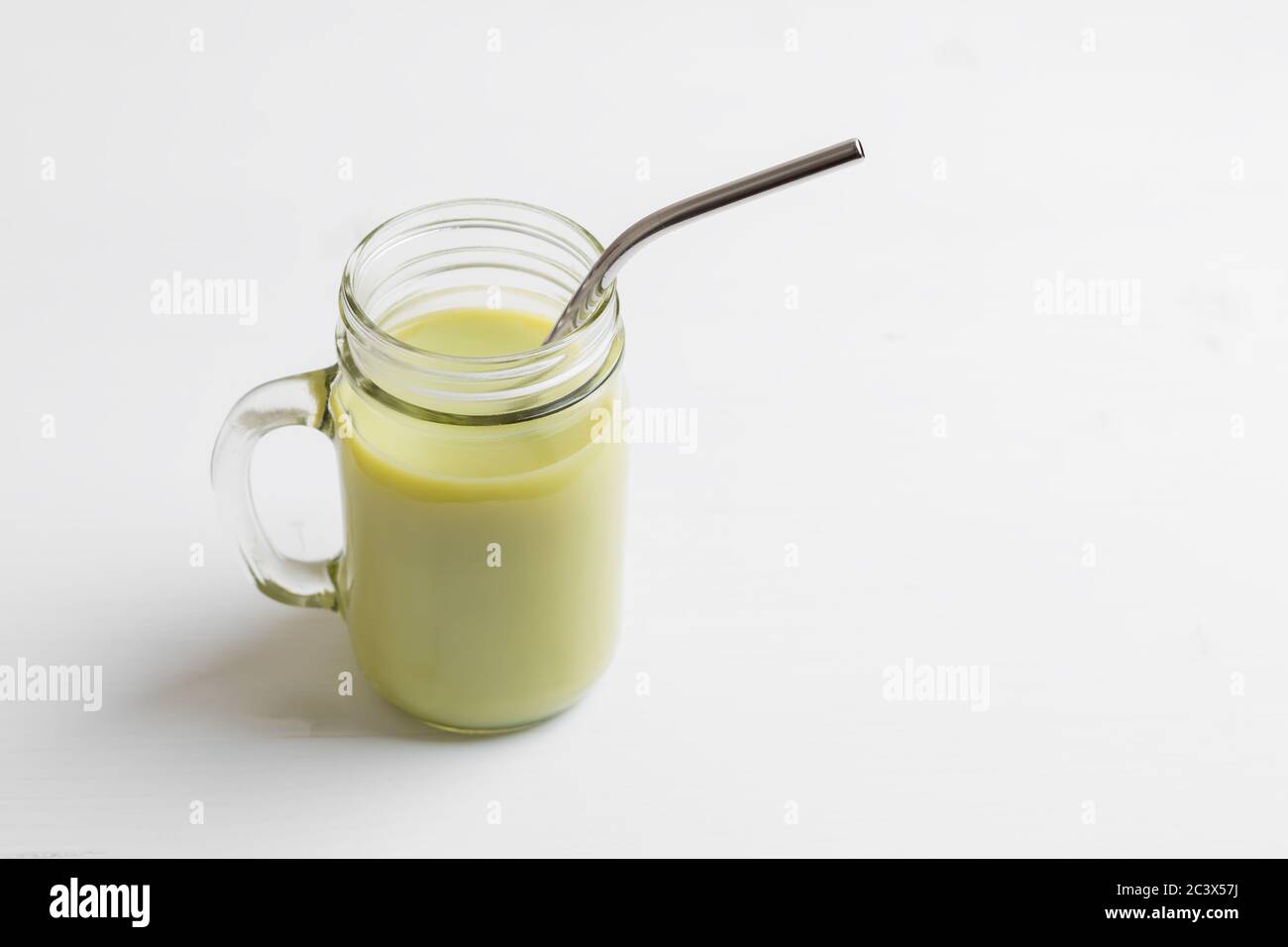 Matcha green tea latte in glass jar with metal tube on white background ...