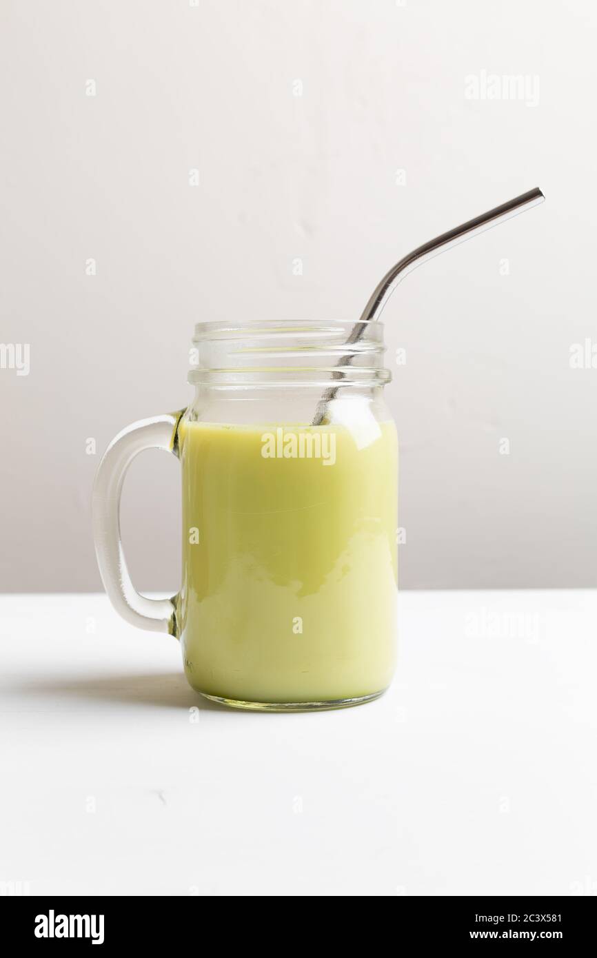 Matcha green tea latte in glass jar with metal tube on white background ...
