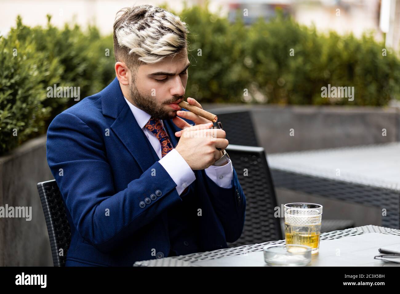 Stylish handsome man smoking cigar and drinking whiskey at a cafe Stock ...