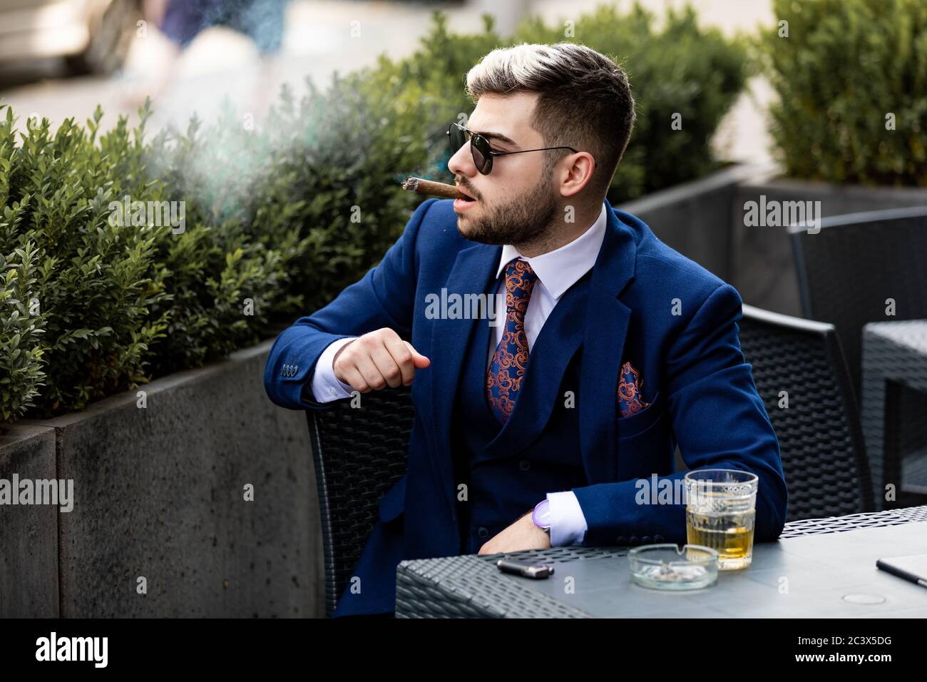 Stylish handsome man smoking cigar and drinking whiskey at a cafe Stock ...