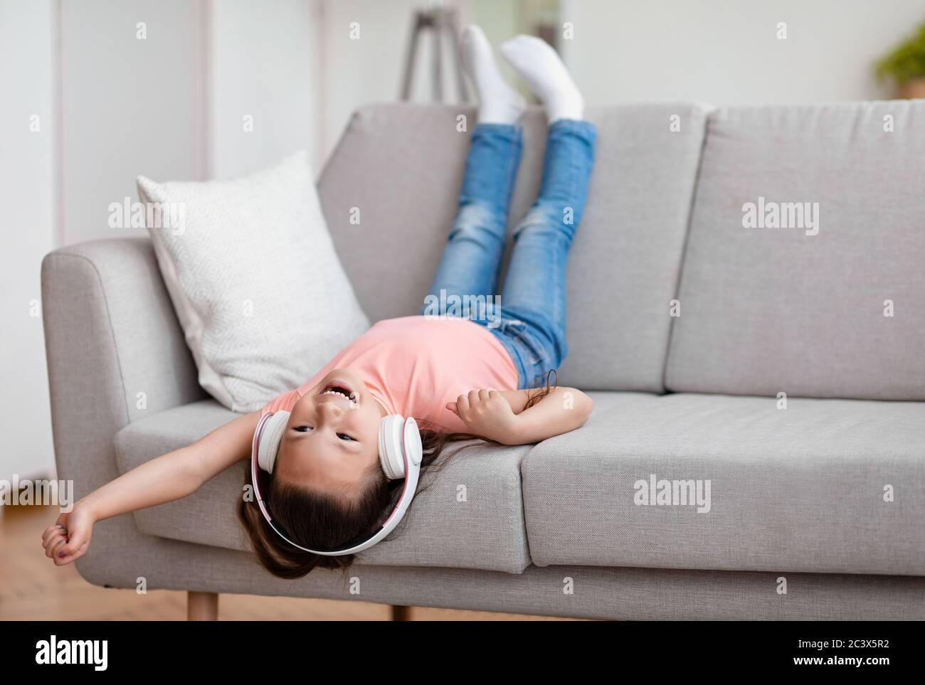 Girl Listening Music Having Fun Sitting Upside-Down On Sofa Indoors ...