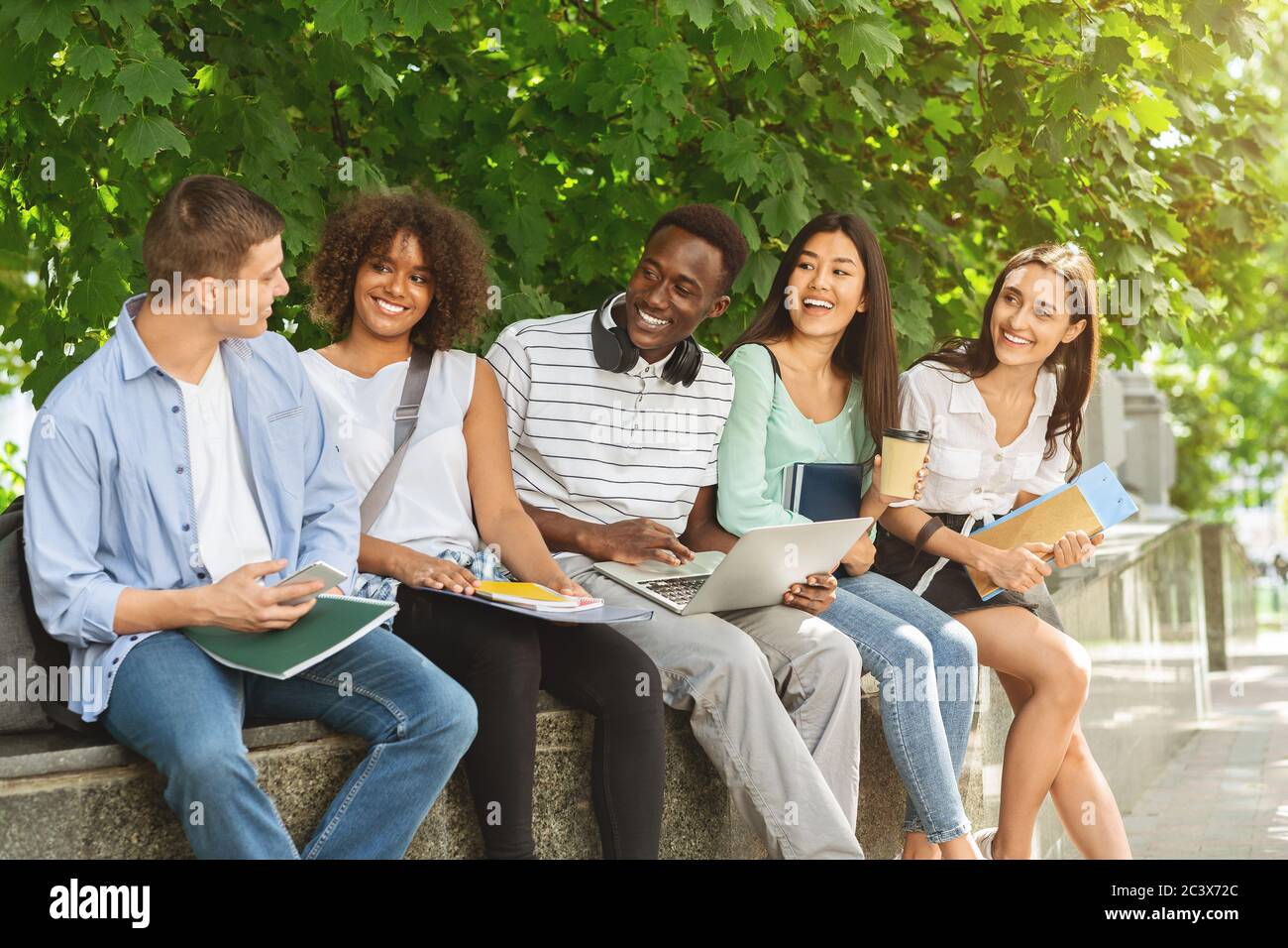Group of multicultural students sitting in the university courtyard ...