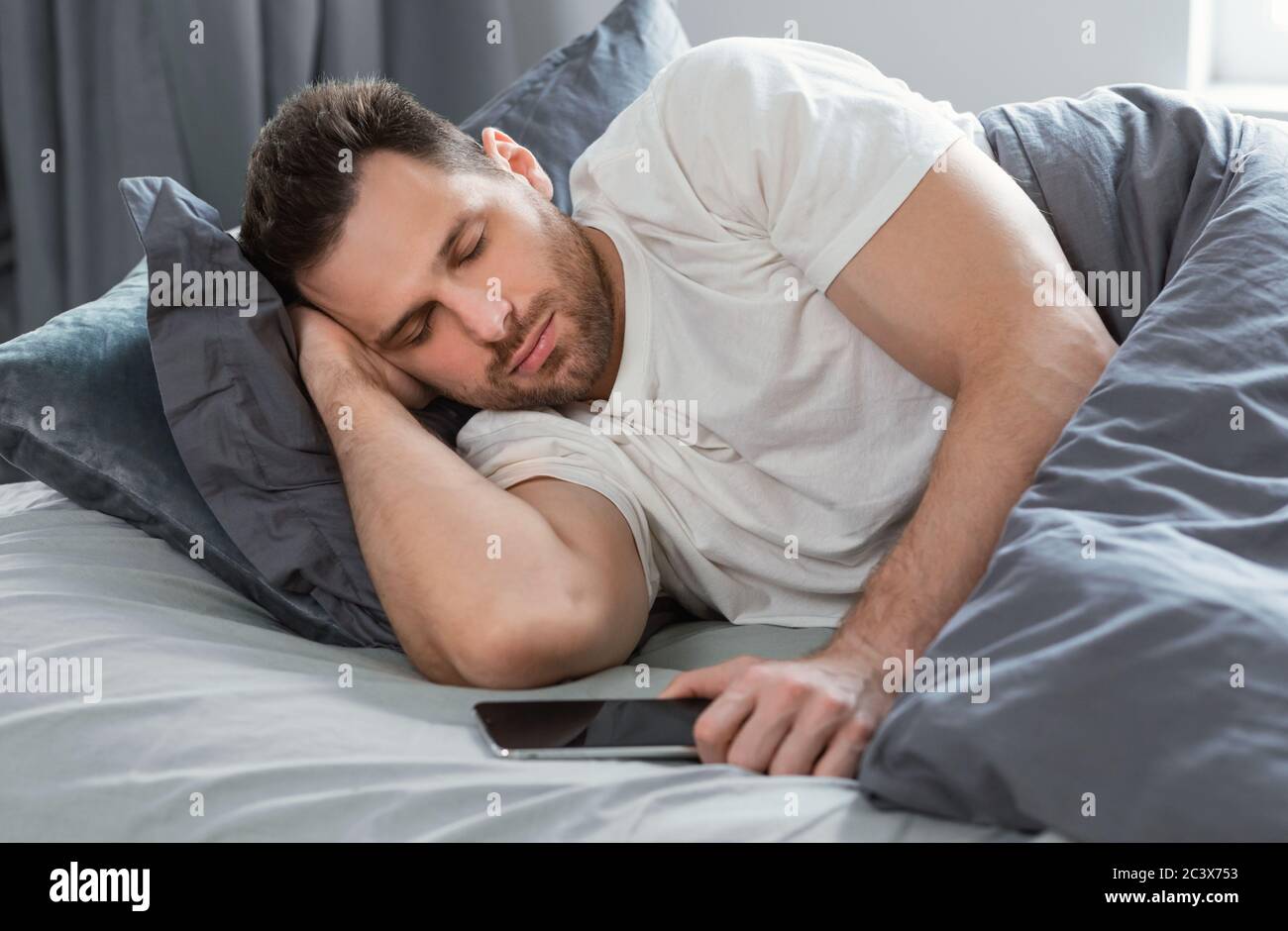 Man Sleeping Holding Mobile Phone Lying In Bed At Home Stock Photo - Alamy