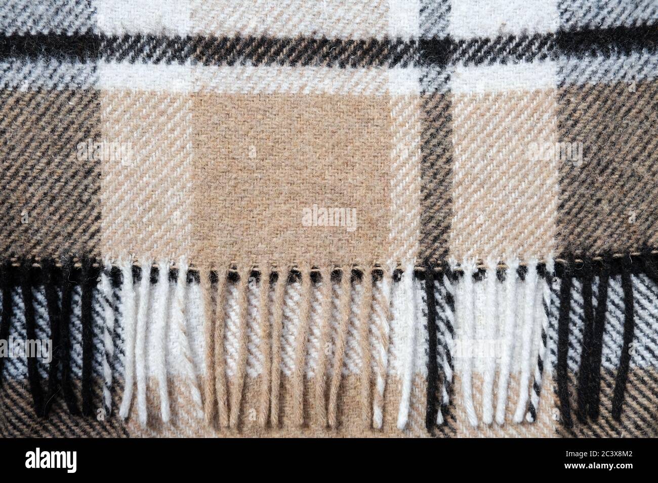 Brown plaid blanket with long edges in the bottom. Close up view of a ...