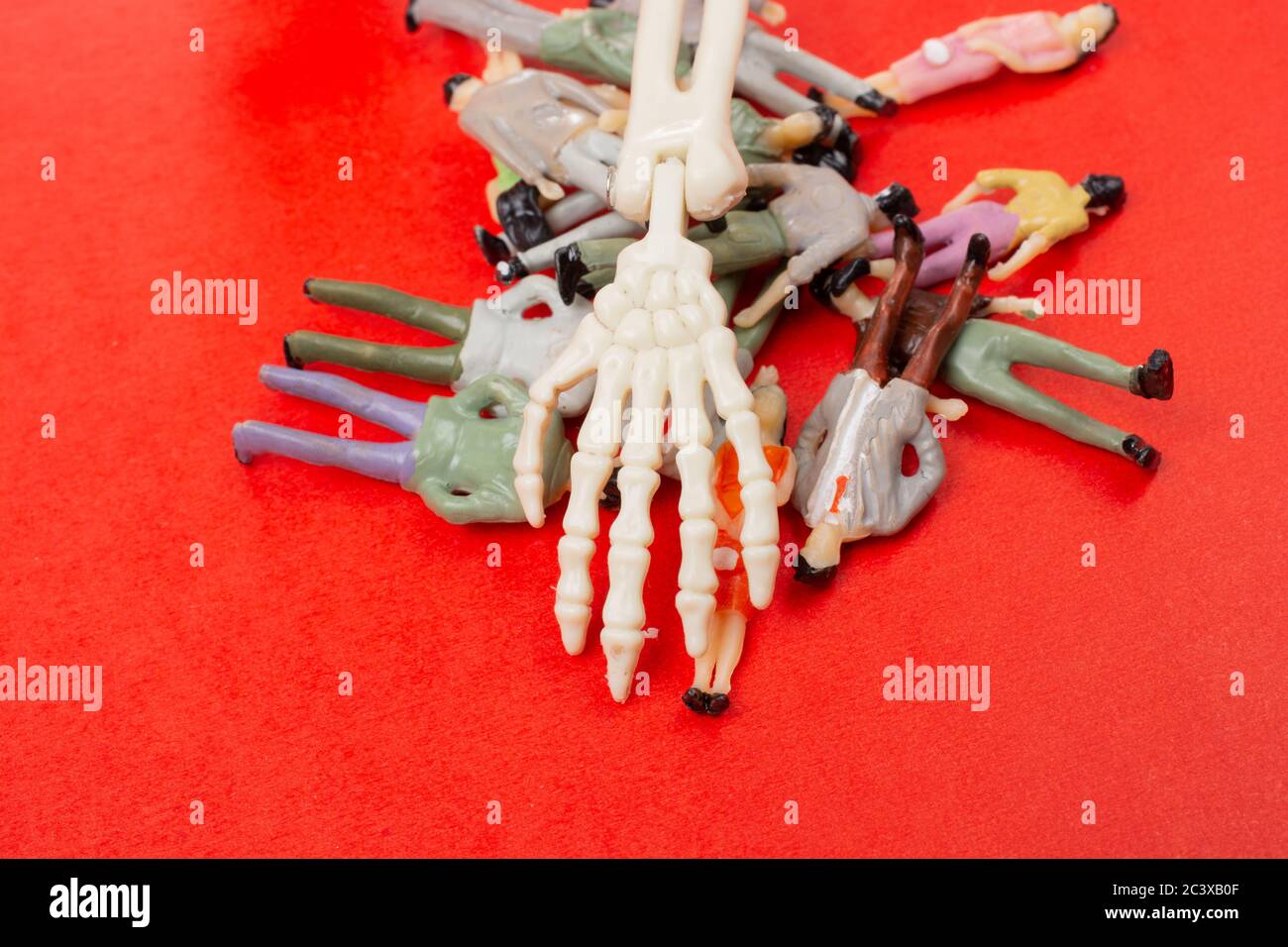 Skeleton hand pressing on people figurine on red. Death concept Stock ...