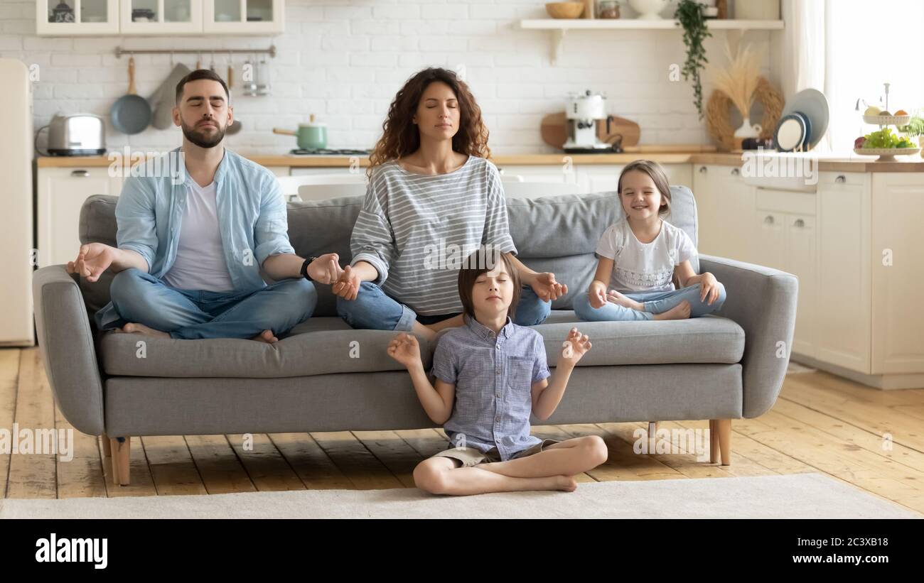 Relaxed young family with cute children sitting and meditating Stock ...