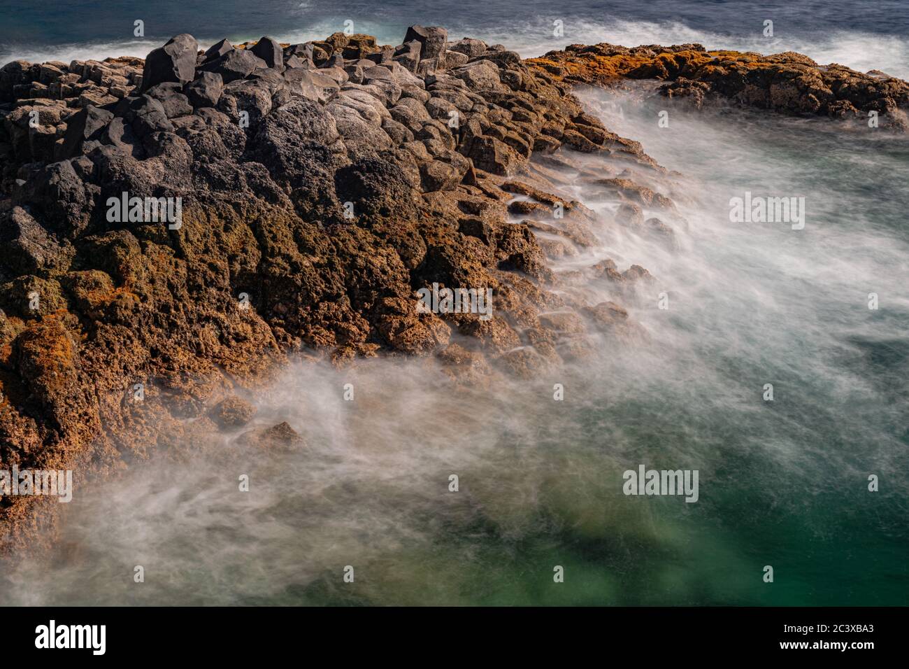 Volcanic rocks in Atlantic ocean, long exposure photography, with ...
