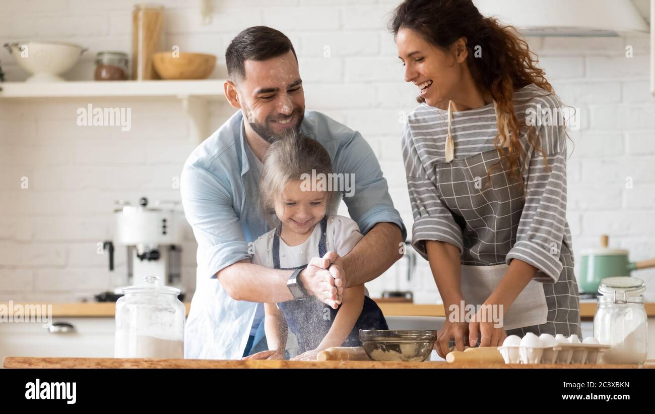 Happy father clapping hands with flour hugging daughter near mother ...
