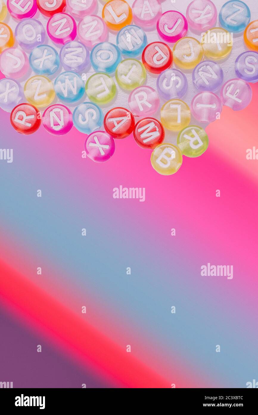 Multi color alphabet letter beads placed randomly on white background ...