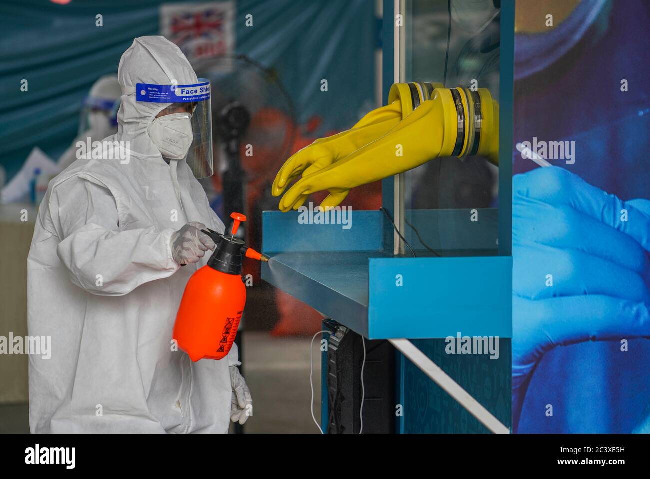 An employee wearing a personal protective Equipment suit (PPE) uses ...