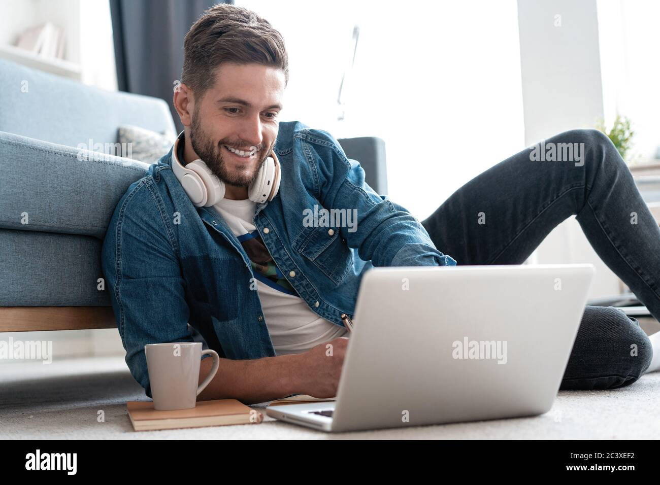 Smiling young man making video call with friends at his modern home ...