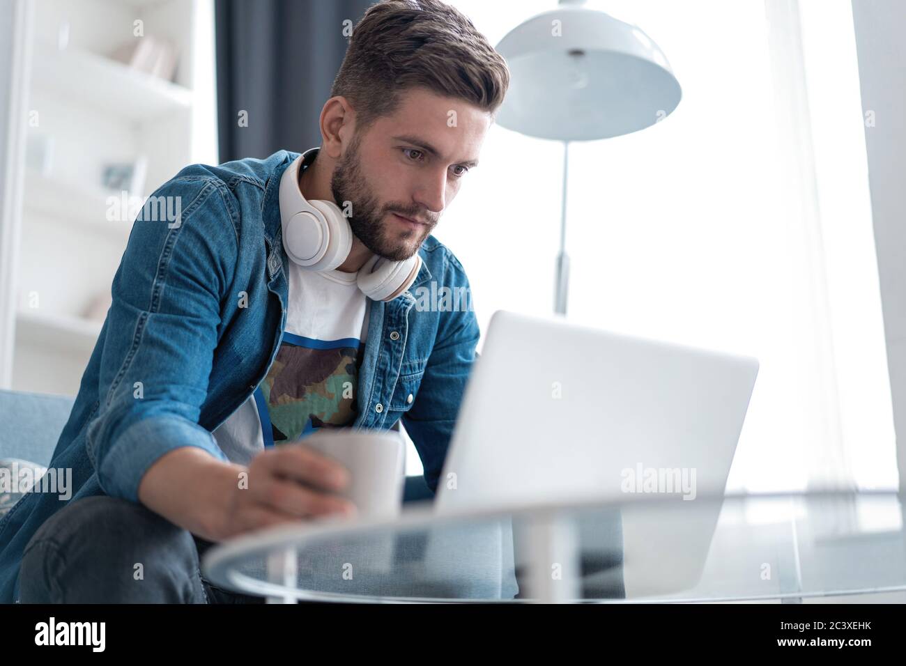 Smiling young man making video call with friends at his modern home ...