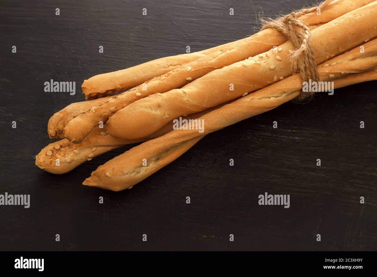 Bread sticks tied with a rope against a dark background. View from ...
