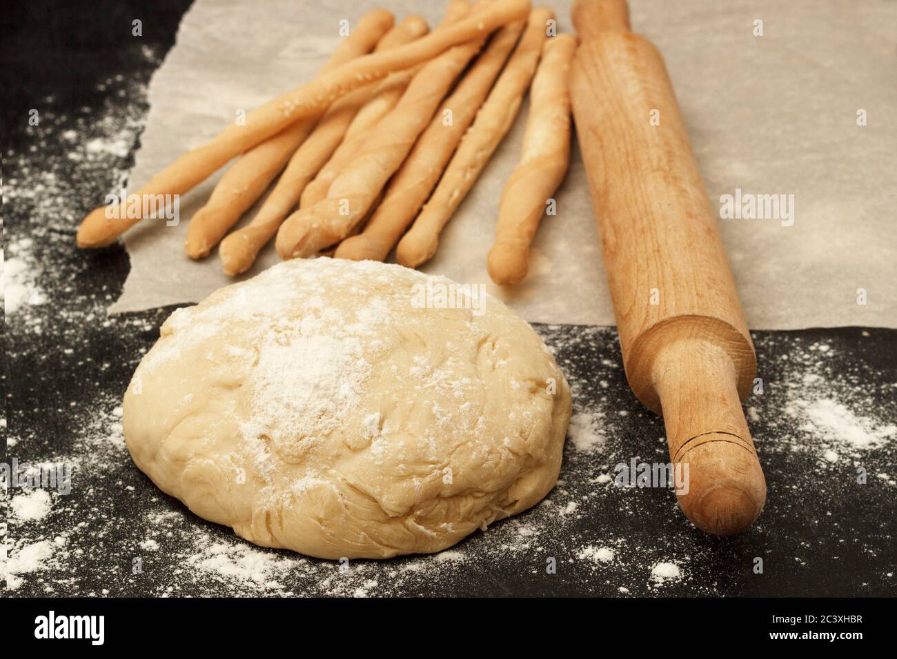 Bread sticks on paper and a piece of dough with a rolling pin Stock ...
