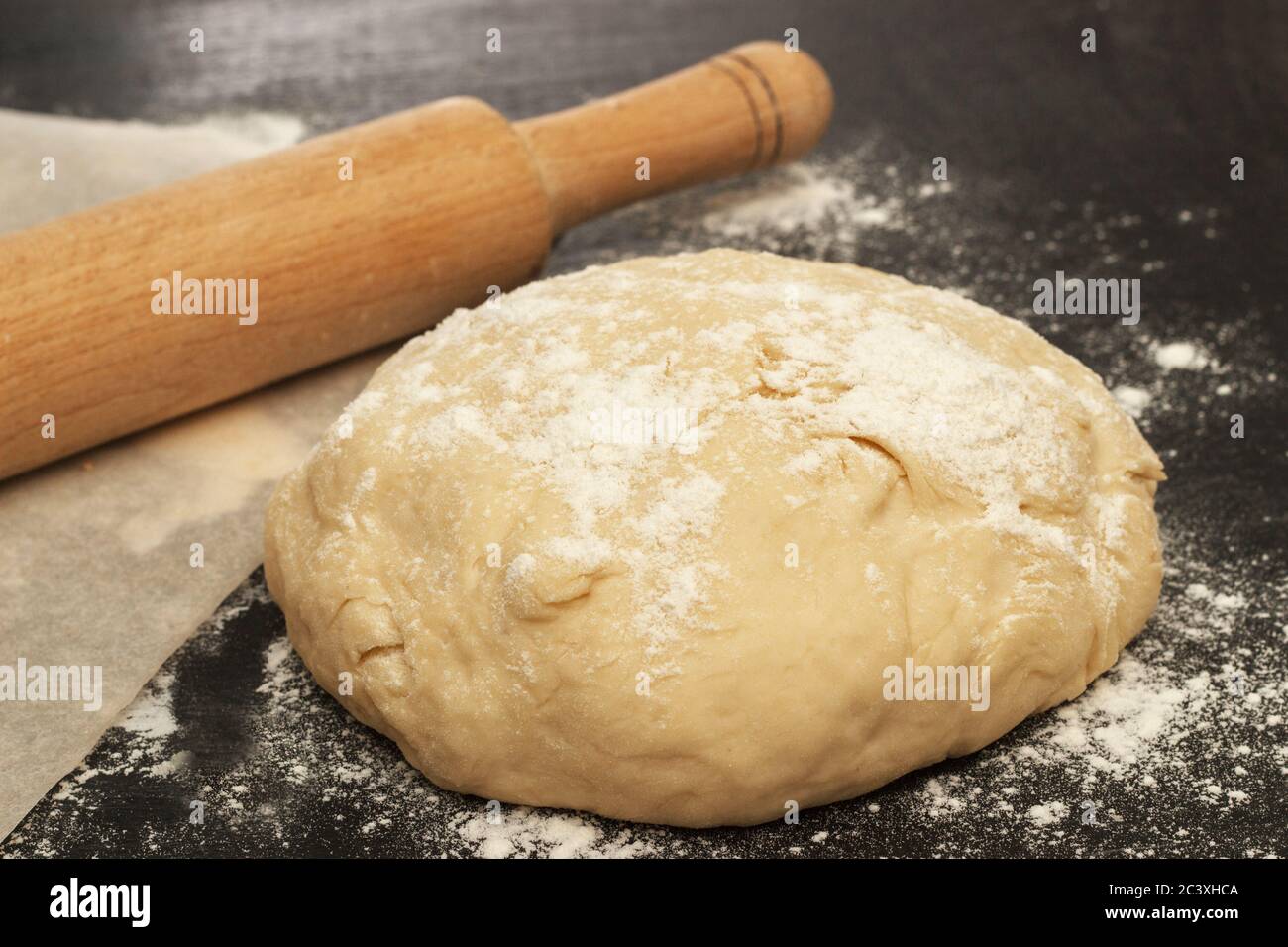 round dough and rolling pin on a dark background Stock Photo - Alamy