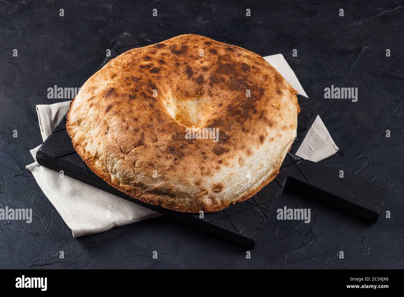 Round Armenian pita bread on a board and napkin on a dark background ...