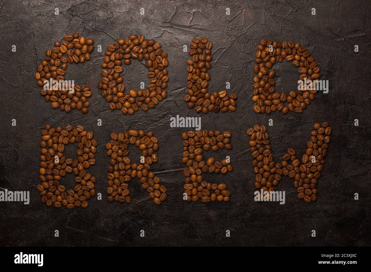 Text cold brew laid out from coffee beans on a dark concrete background ...