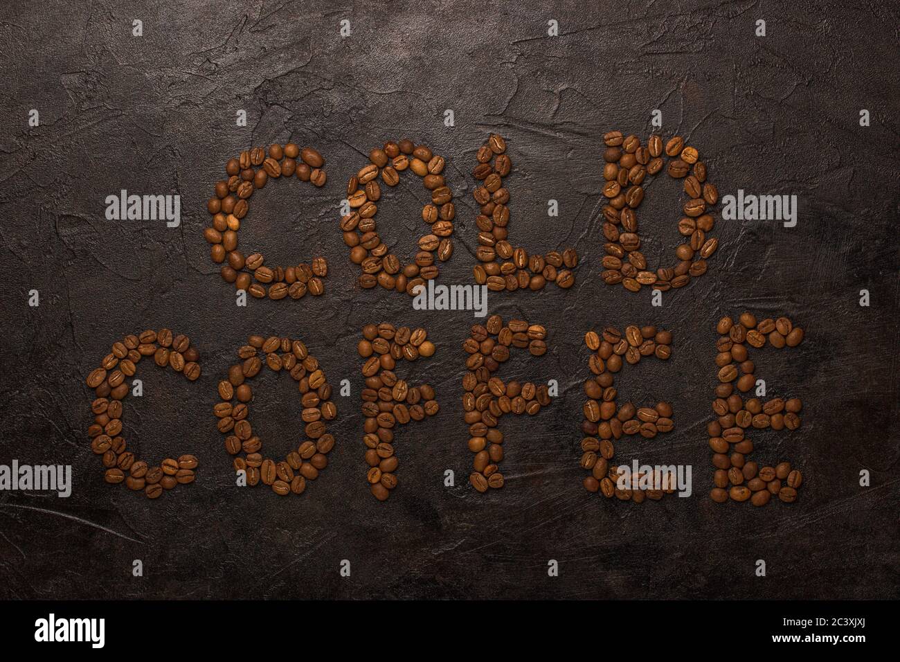 Text cold brew laid out from coffee beans on a dark concrete background ...