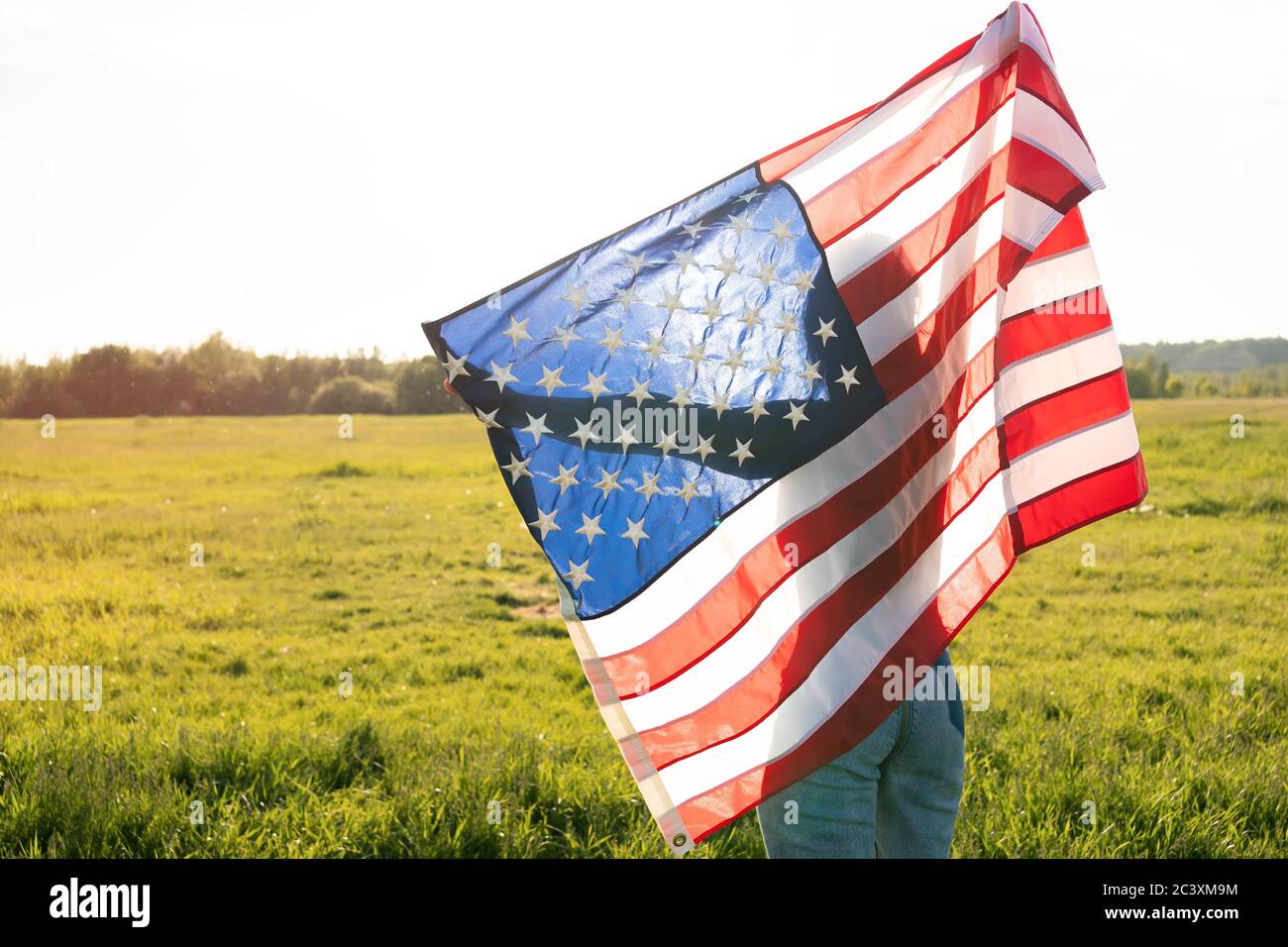 Woman holding an American flag above her head on the park field during ...