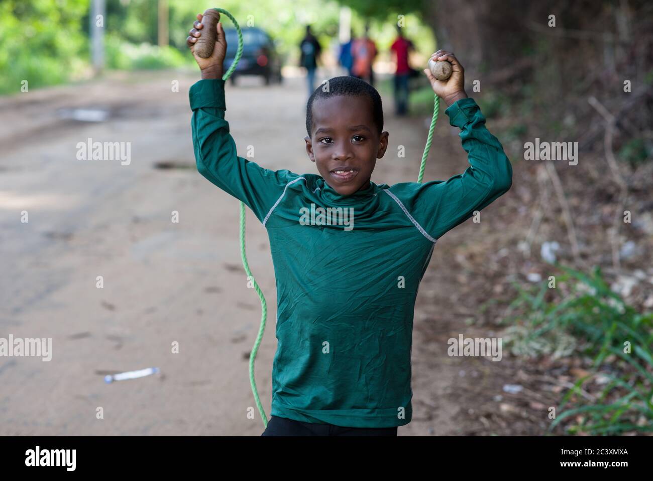 young boy in sportswear jumping rope and looking at camera smiling ...