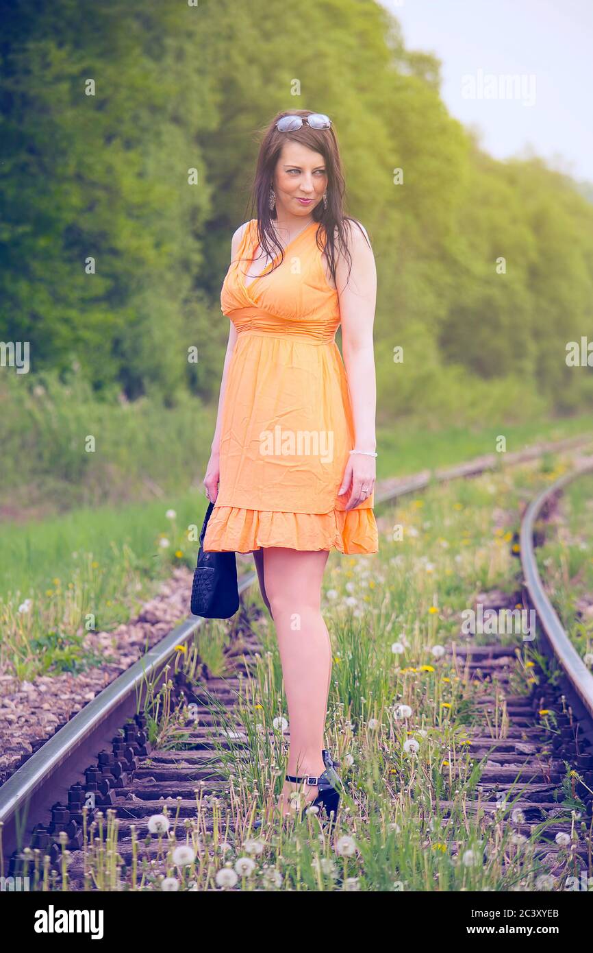 Pretty woman in dress standing on the train tracks Stock Photo - Alamy