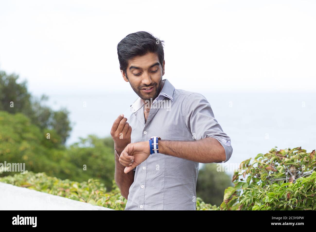Annoyed young man looking at his smartwatch waiting for public ...