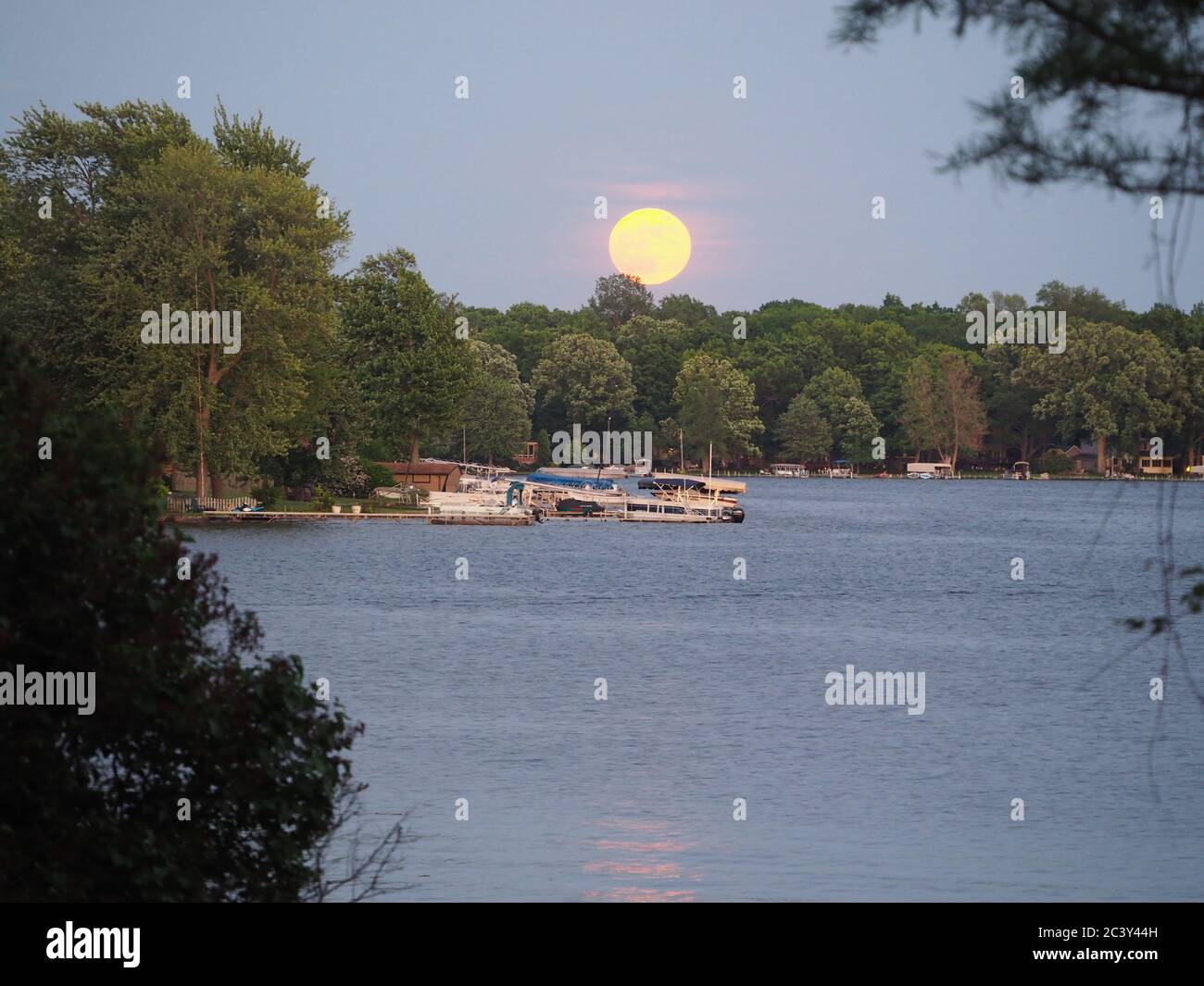 Moon Rising Through Pink Clouds Over a Lake Stock Photo - Alamy