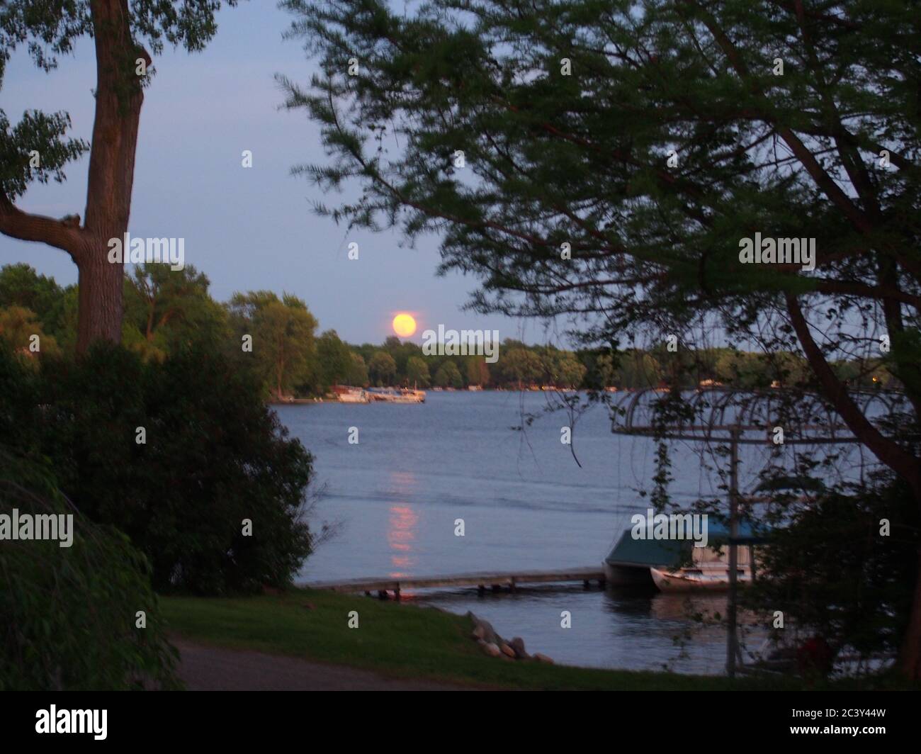 Moon Rising Through Pink Clouds Over a Lake Stock Photo - Alamy