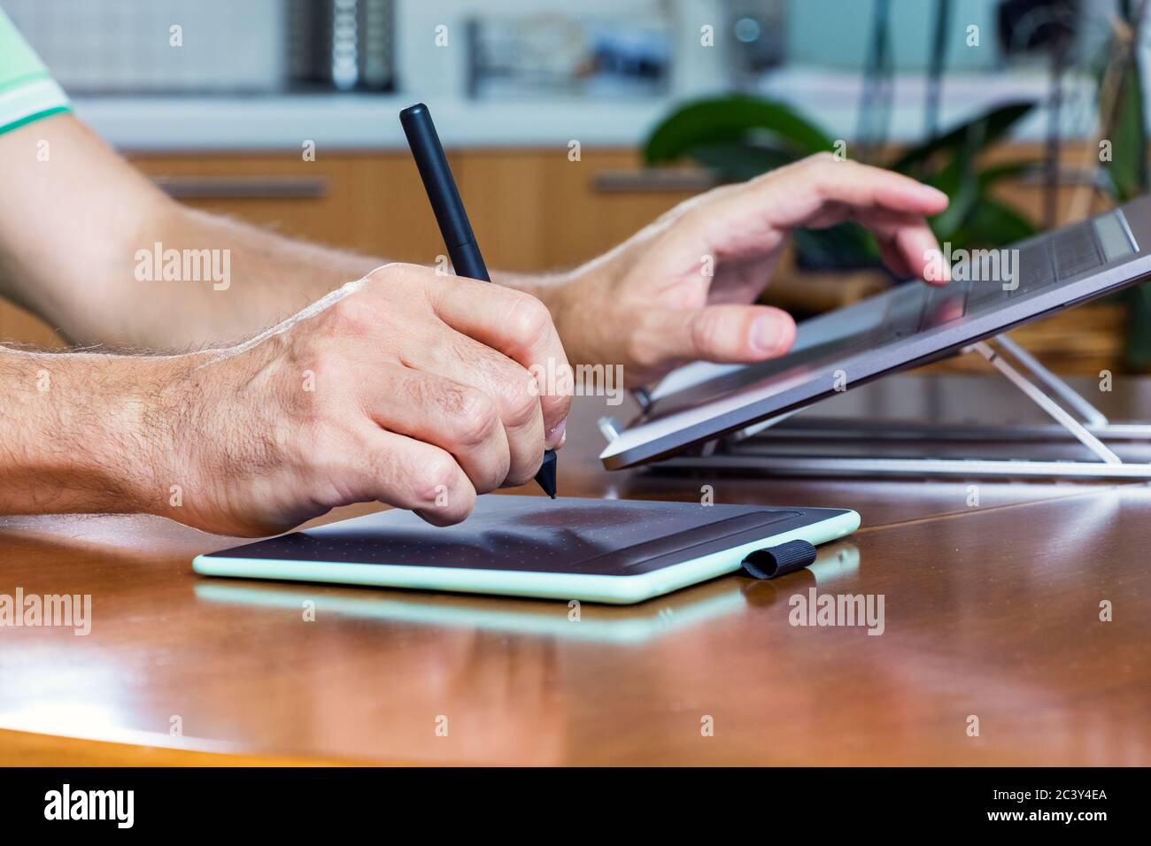 Male designer hands using a drawing graphics tablet and a laptop while ...