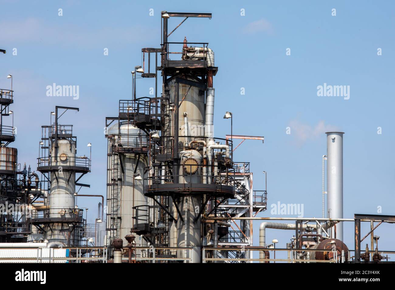 Petro chemical refinery pipes and cracking towers against a blue sky ...