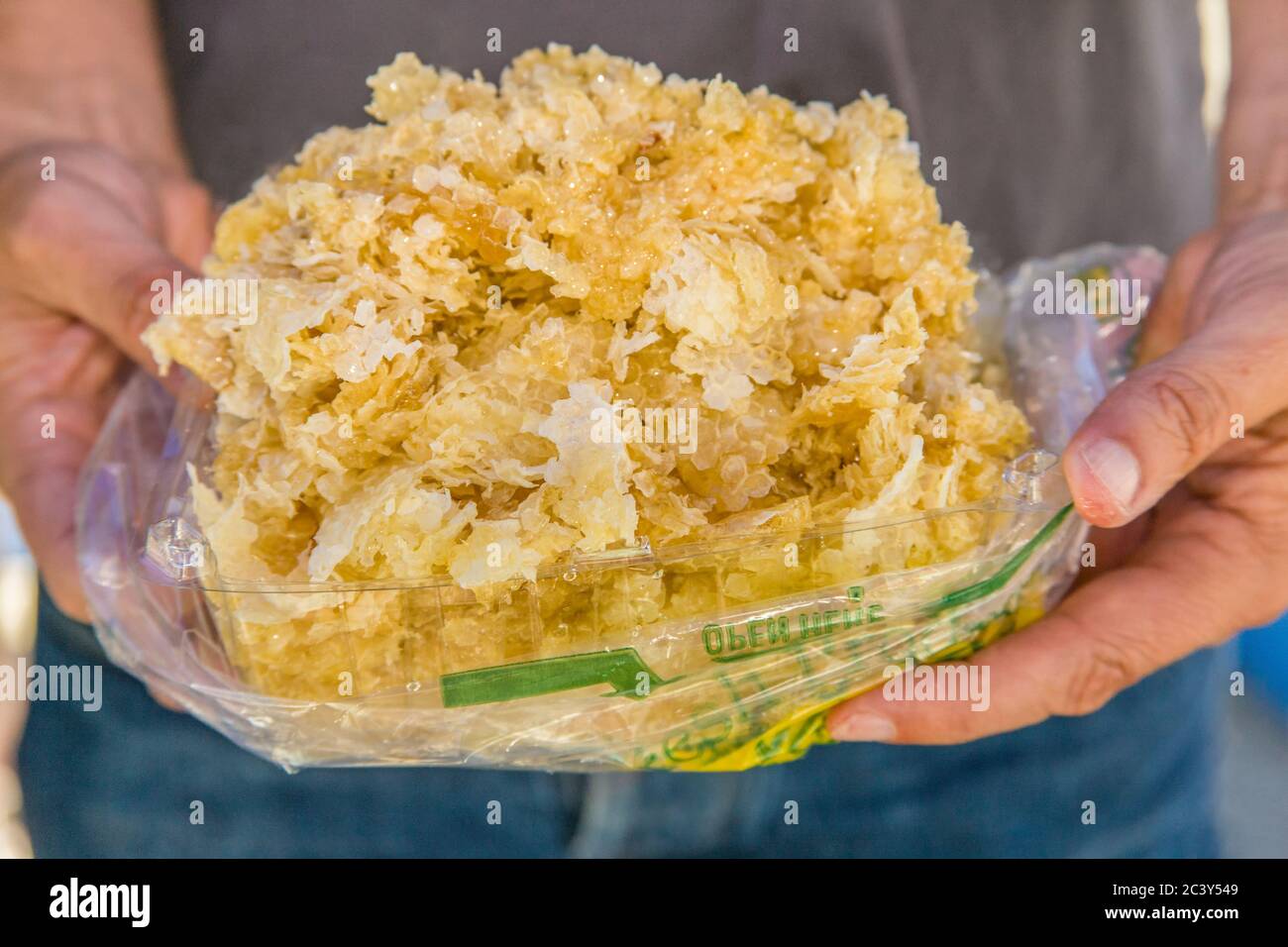 Man holding a container of wax cappings from uncapping honey frames ...